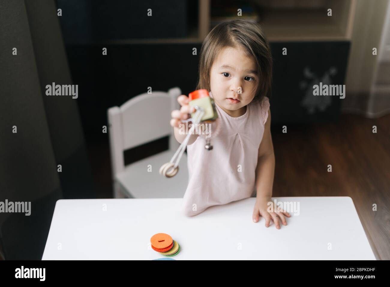 Happy beautiful little two-year-old girl is holding educational toy in ...