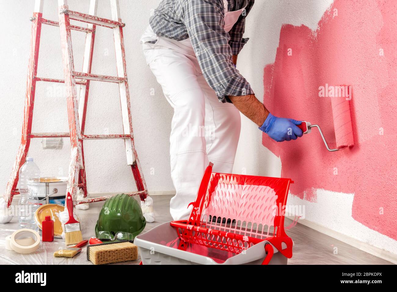 Caucasian house painter worker in white work overalls, with the roller ...