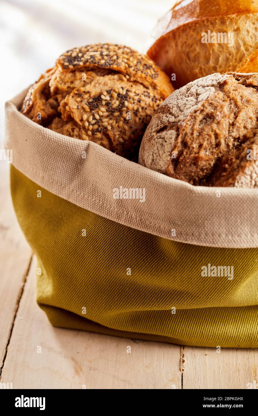 Fabric bag with freshly baked buns of brown and white bread, viewed in ...