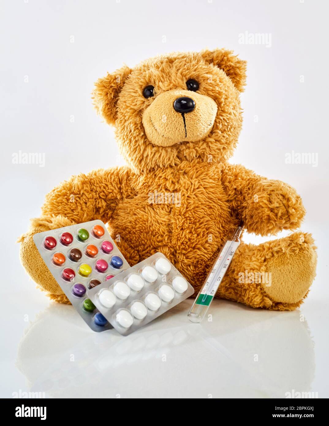 Toy bear with medicine, thermometer and colorful pills in blister pack ...