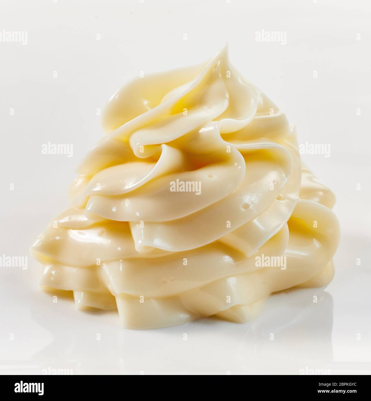 Decorative twist of gourmet homemade mayonnaise over white with ...