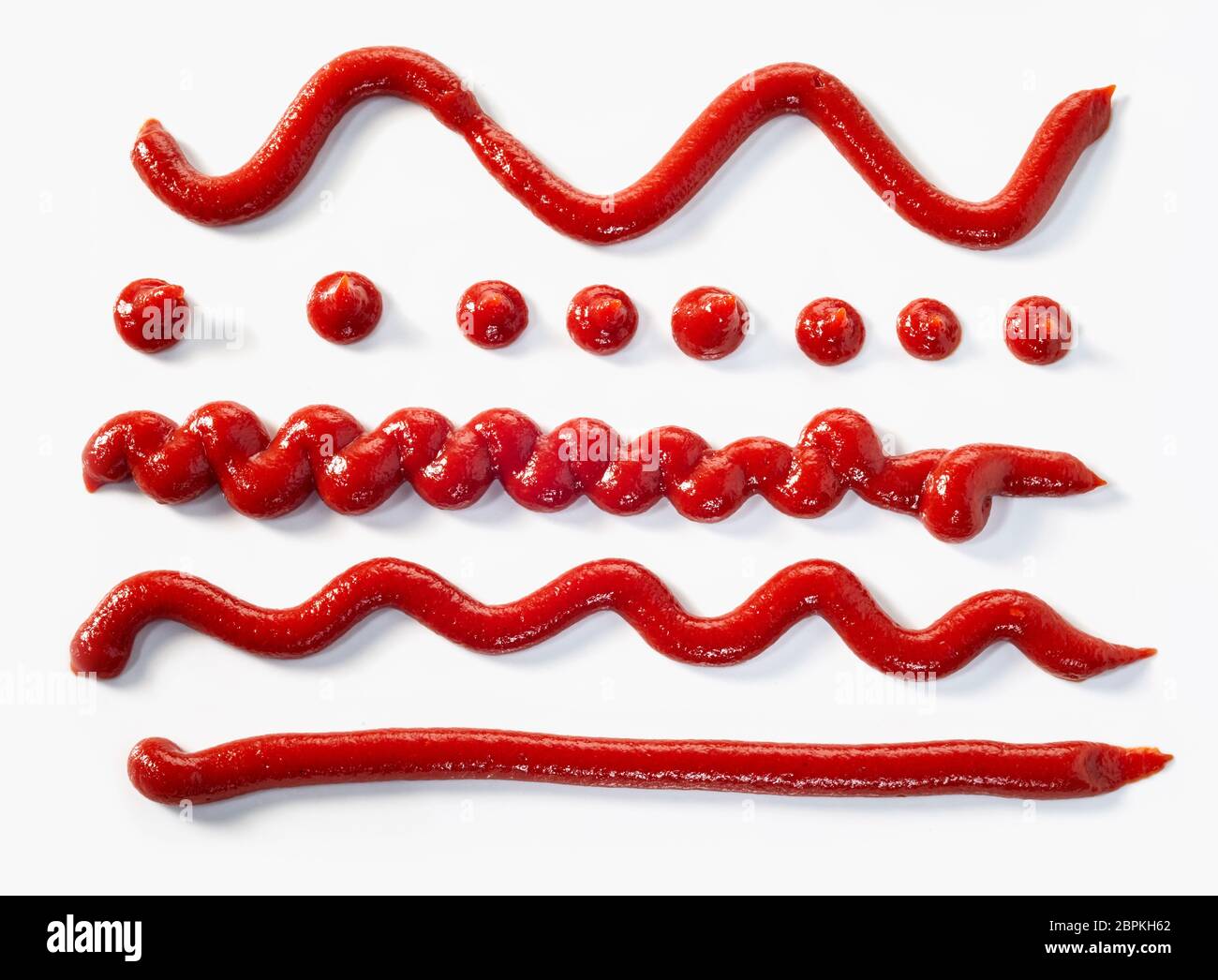 Assorted squiggles, wavy lines and dots of tomato sauce dispensed from ...