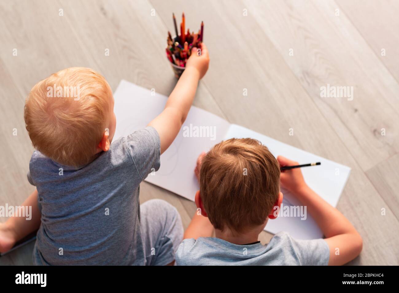 Two little boys drawing with pencils on the floor in his room. Stay at ...