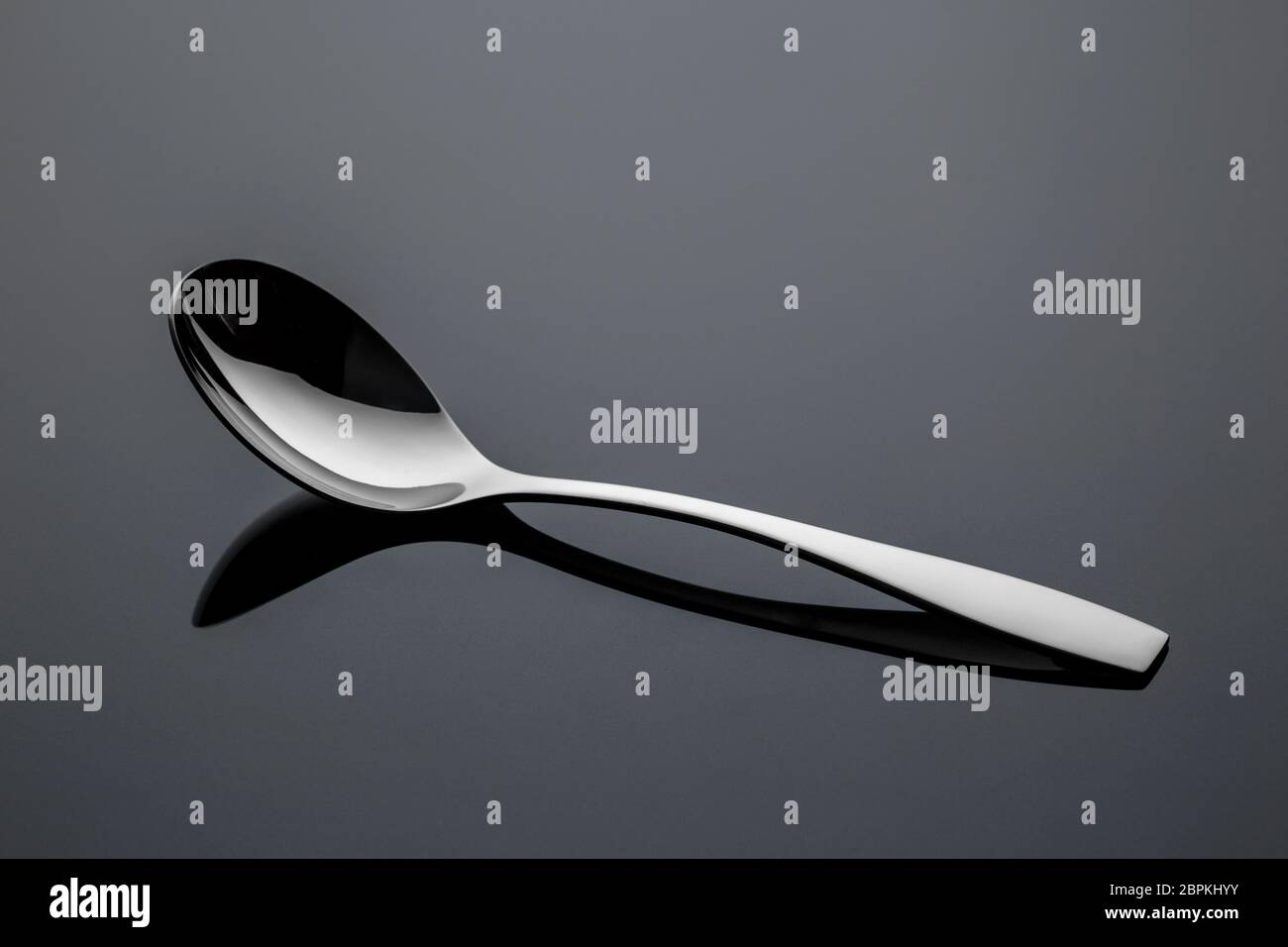 Stainless steel metal spoon on a reflective surface Stock Photo - Alamy