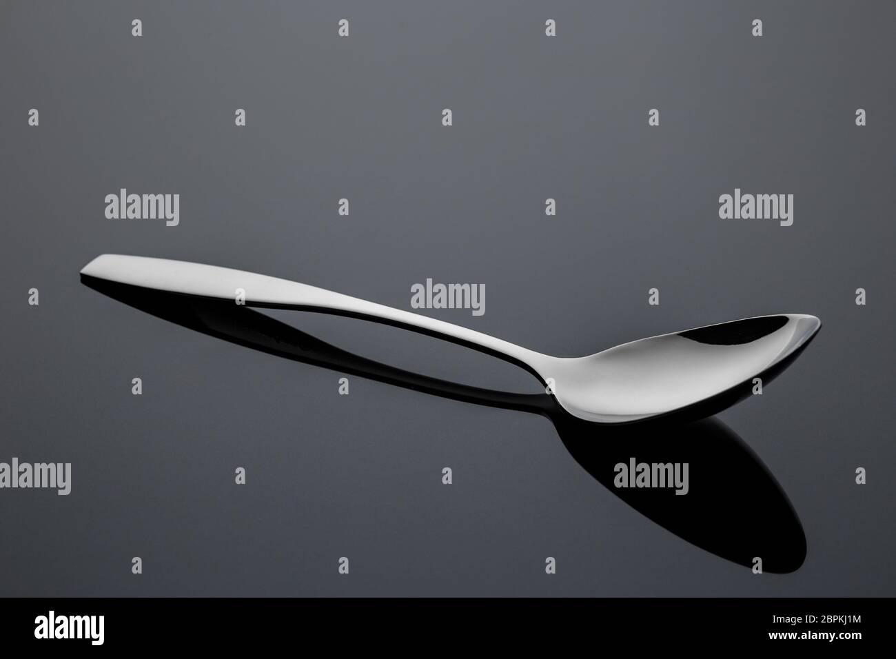 Stainless steel metal spoon on a reflective surface Stock Photo - Alamy