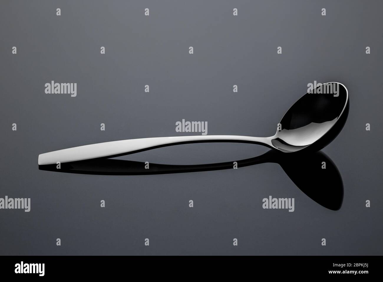 Stainless steel metal spoon on a reflective surface Stock Photo - Alamy