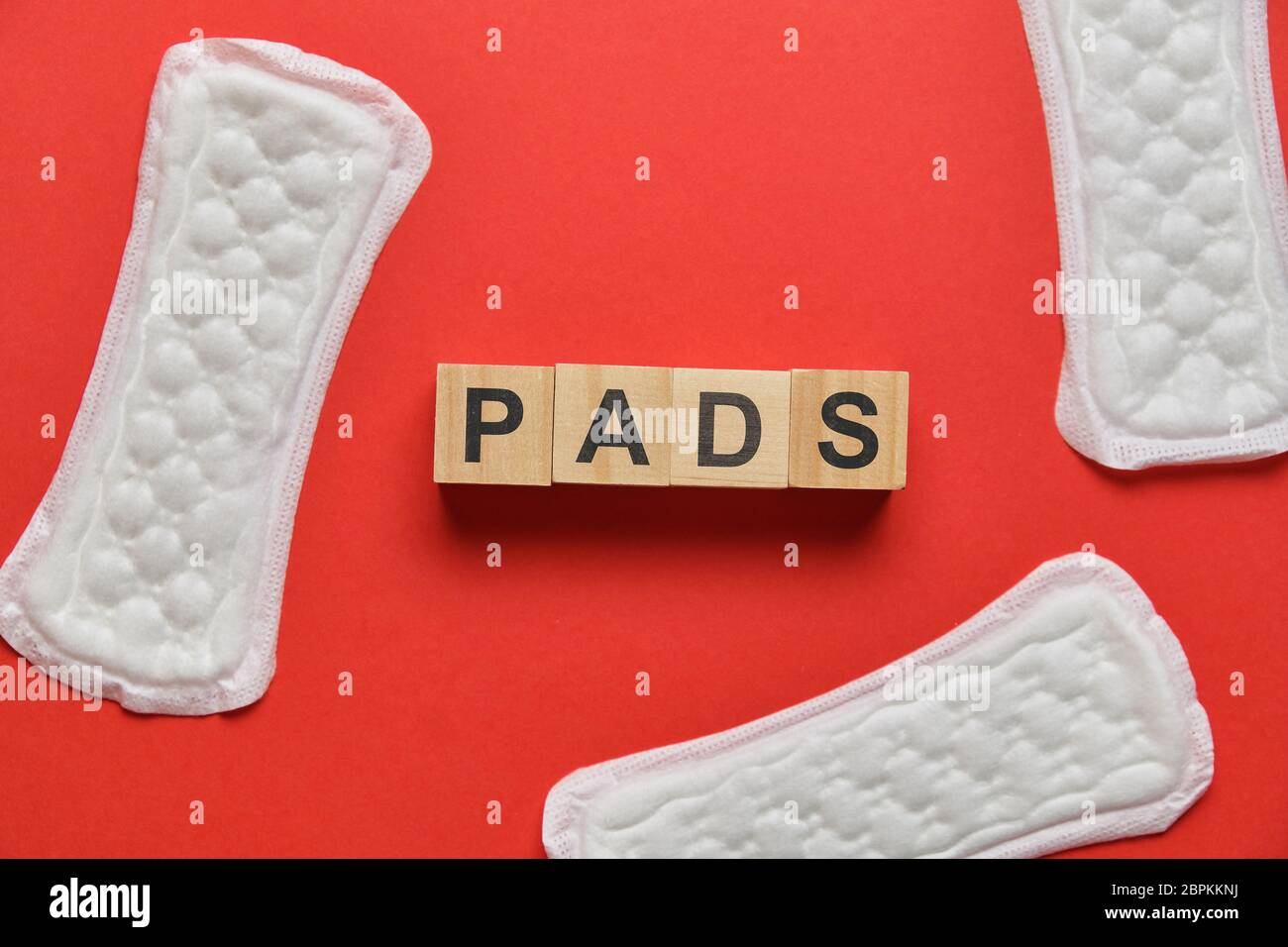 White feminine pads on a red background with the inscription on wooden ...