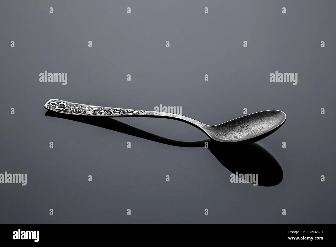 Old nickel silver spoon on a reflective surface Stock Photo - Alamy