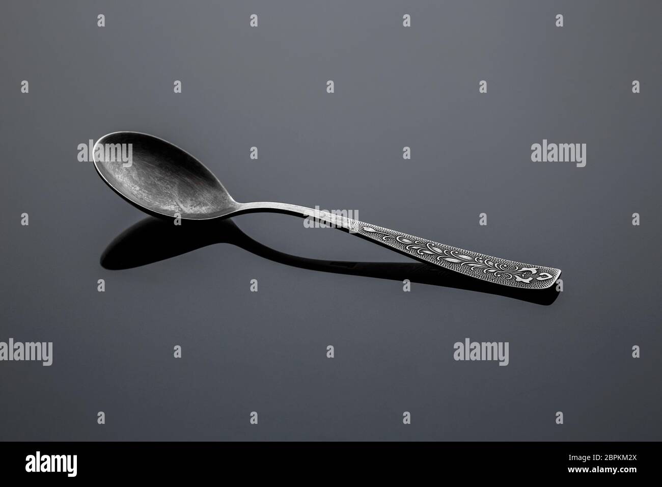 Old nickel silver spoon on a reflective surface Stock Photo - Alamy