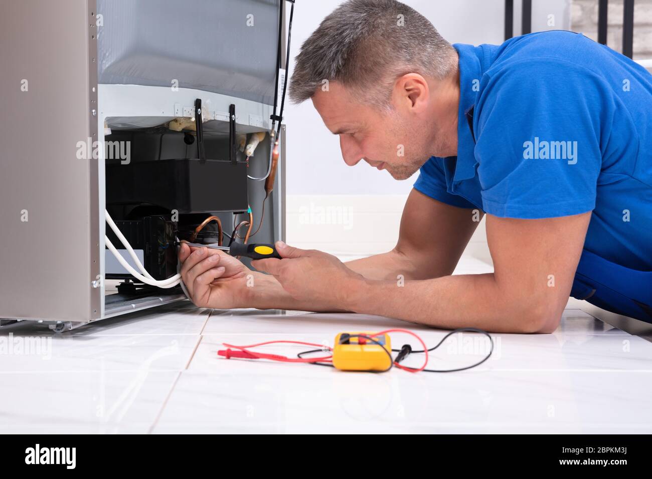 Electrician working on fridge in home hi-res stock photography and ...