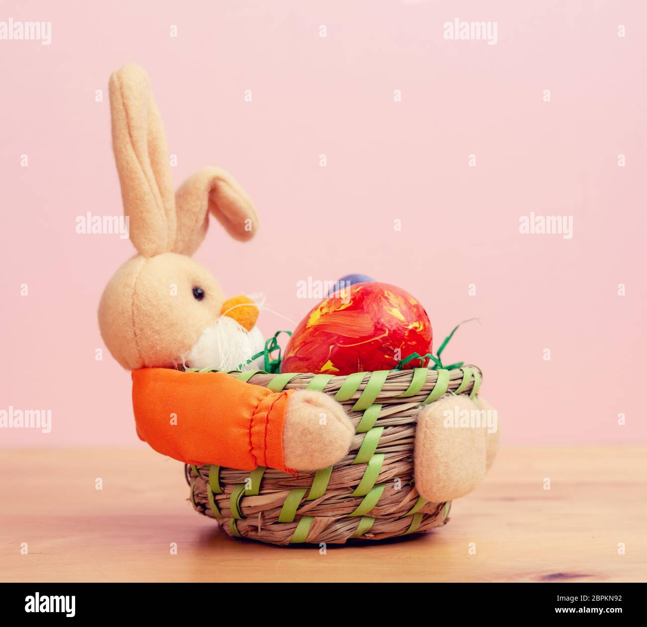 easter bunny in basket with egg in front of pink background Stock Photo ...