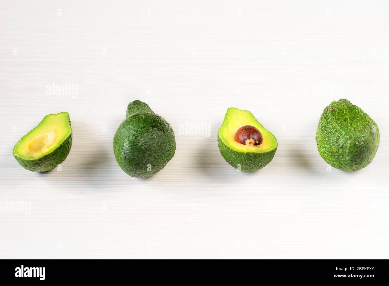 Isolated avocado. Whole avocado fruits and two halves in a row isolated ...