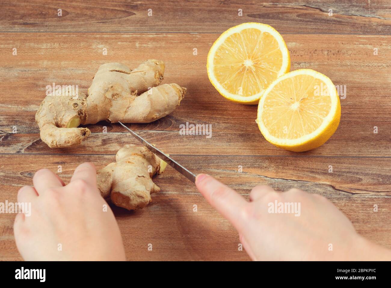 Female hands cut into pieces ginger root for a drink made from fresh ...