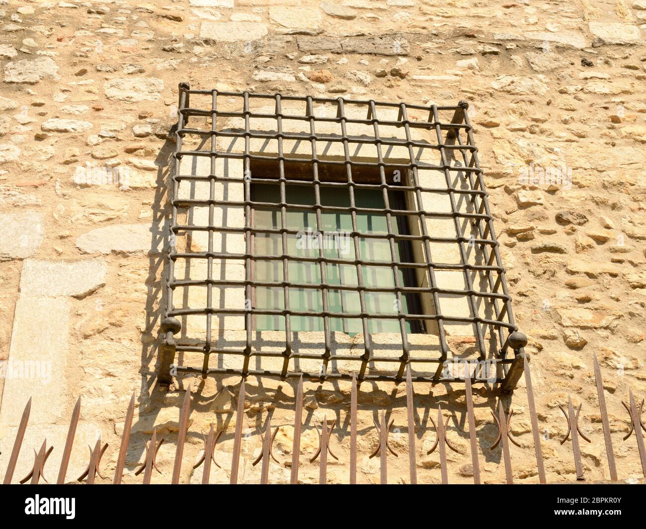 Iron grille window on stone wall in the medieval city of Girona ...