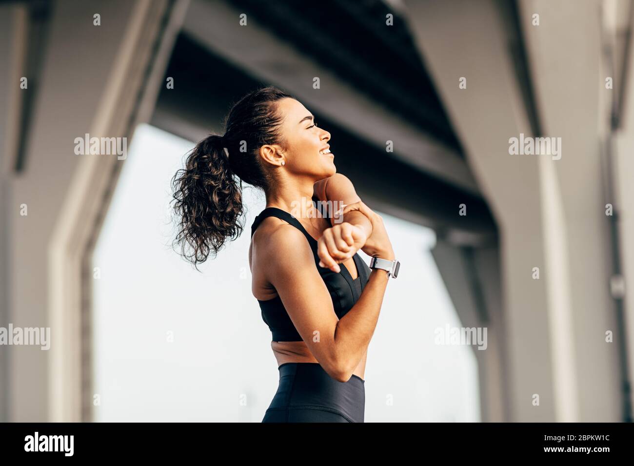 Side view of a fitness woman doing arms stretching exercise under ...