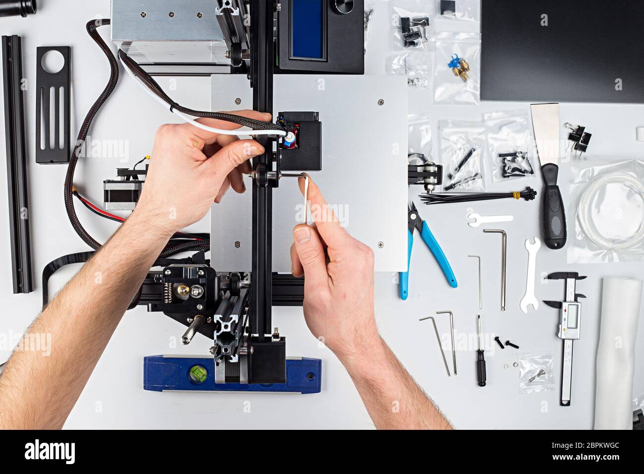 young man student assembly of 3D printer building kit on white table ...