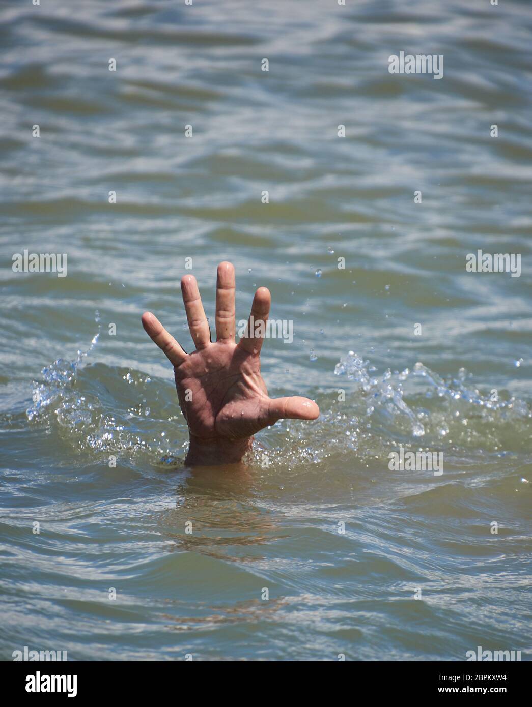 man's hand sticks out from the water in the middle of the ocean, a ...