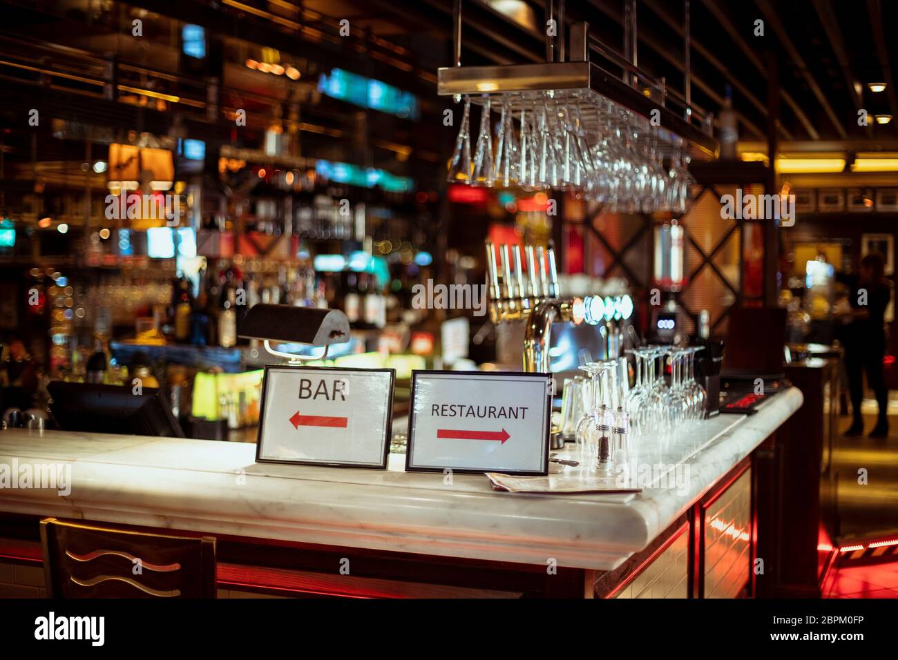 Interior shot of a restaurant bar counter which has signs pointing to ...