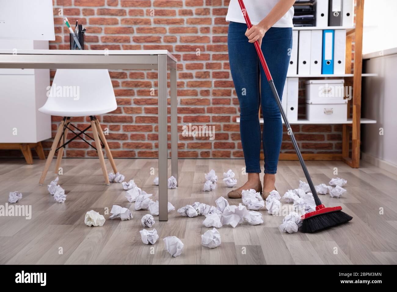 Low Section Of Female Janitor Sweeping Crumbled Paper On Floor With ...
