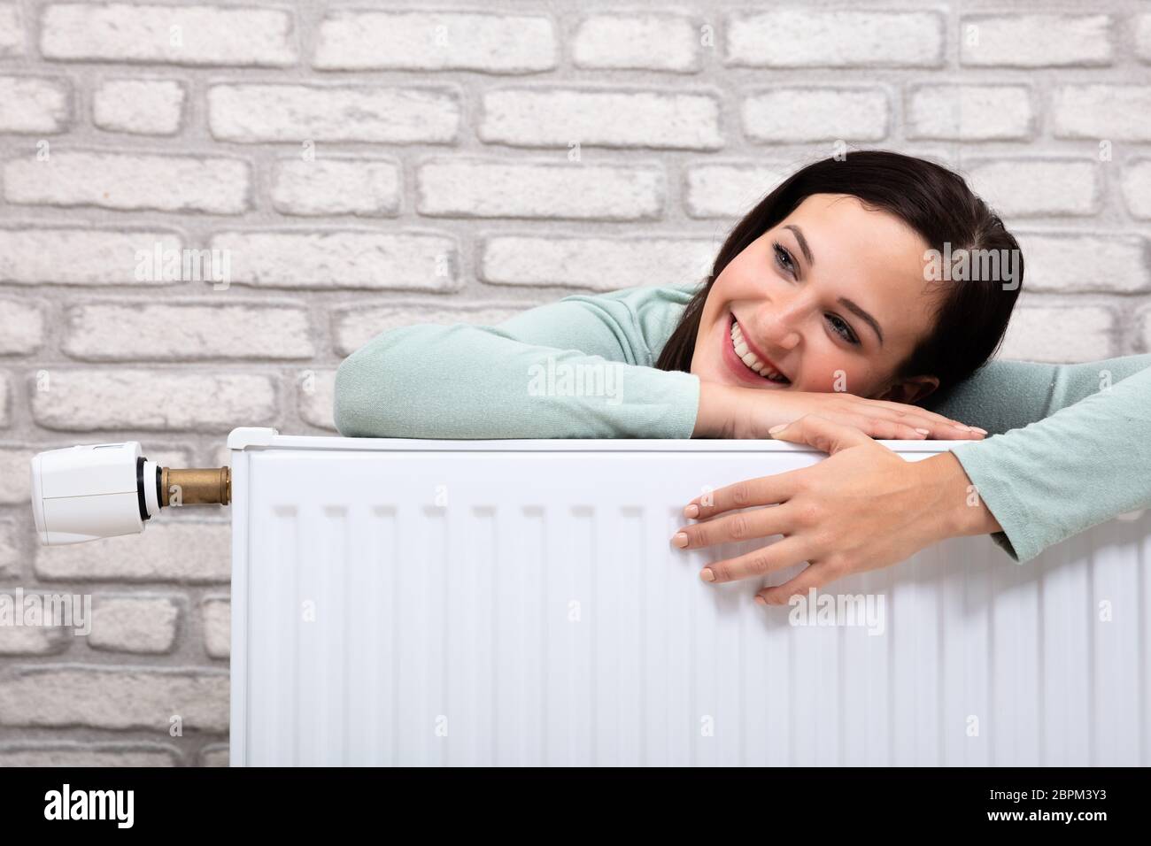 Portrait Of A Happy Young Woman Leaning On Heating Radiator Stock Photo ...