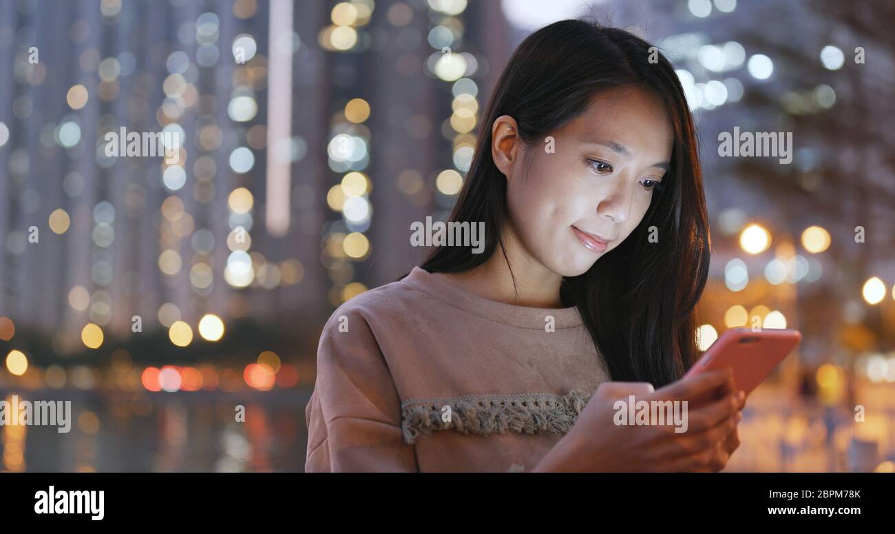 Woman use of smart phone in city at night Stock Photo - Alamy