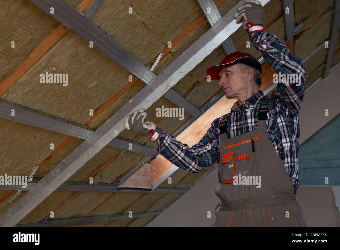 Drywall plaster wall metal fixation. Man holding metal ruler against ...