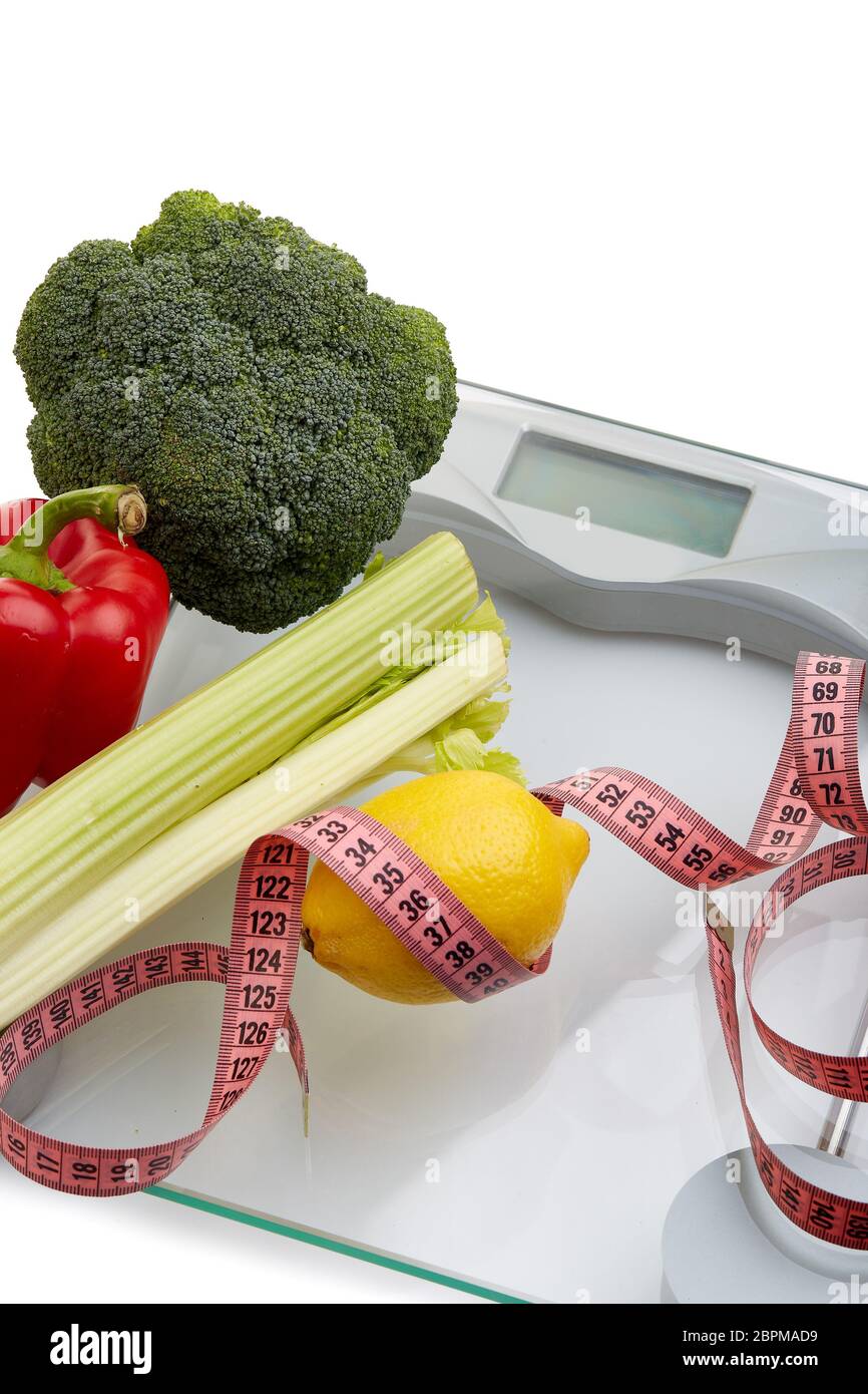 Healthy nutrition. Scales, measuring tape and vegetables on a white ...