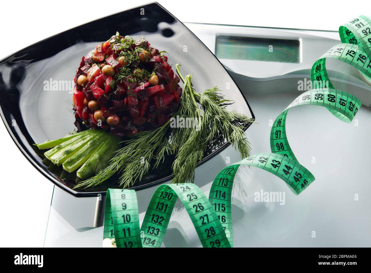 Healthy nutrition. Scales, measuring tape and vegetables on a white ...