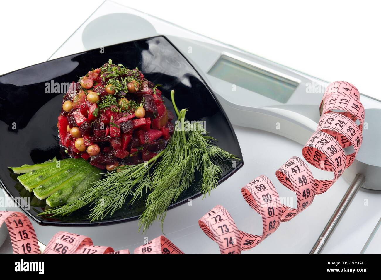 Healthy nutrition. Scales, measuring tape and vegetables on a white ...