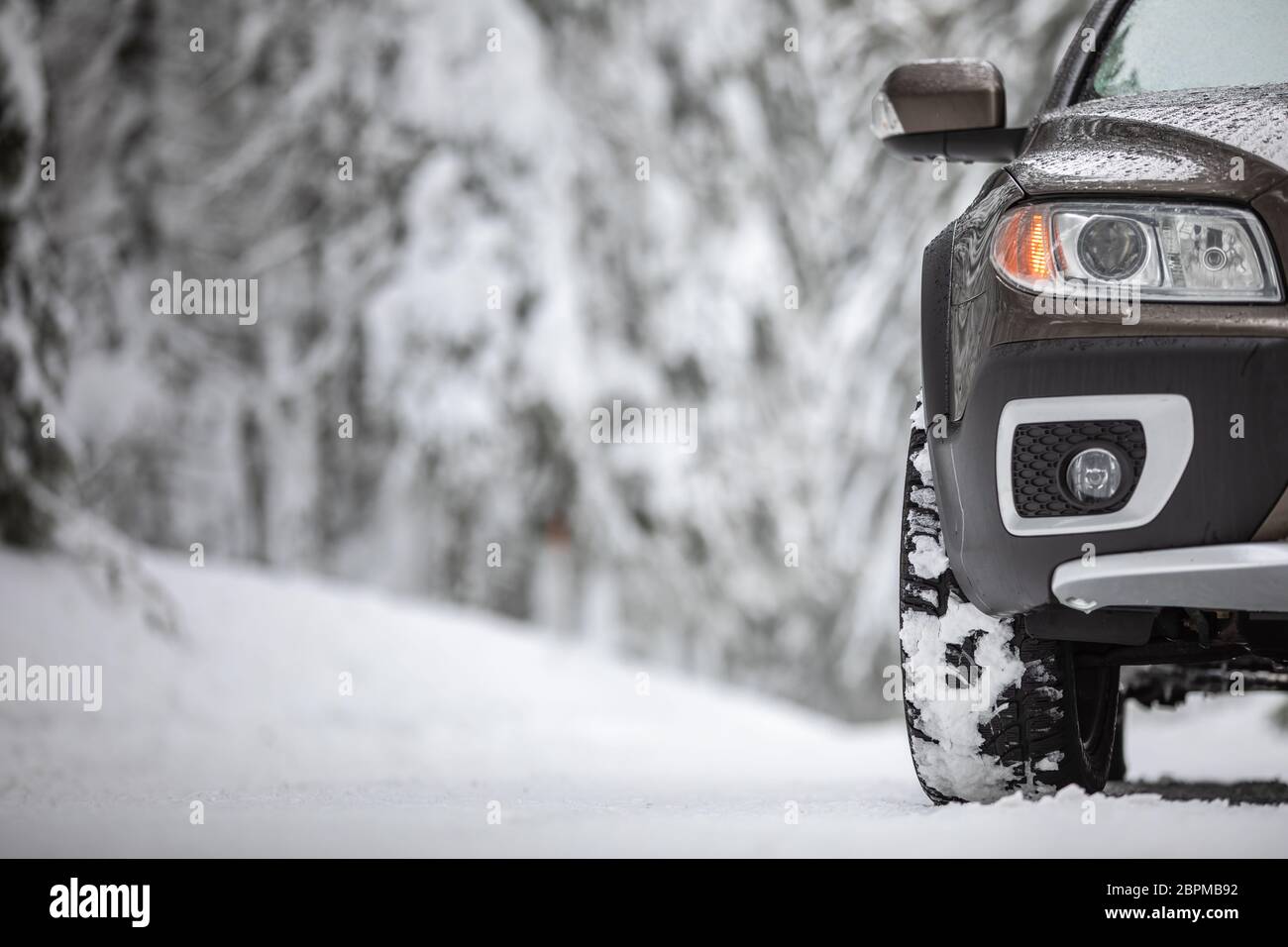 Car on a snowy winter road amid forests - using its four wheel drive ...