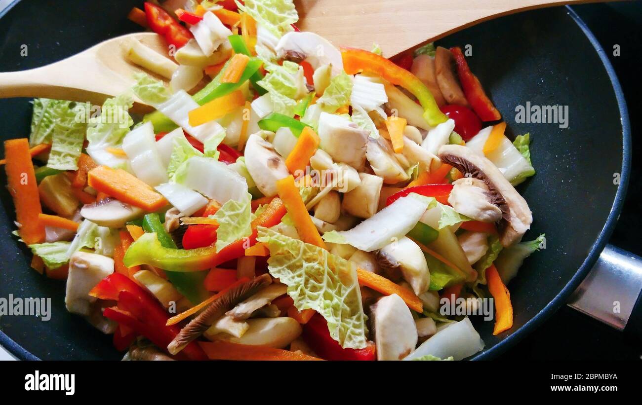 Closeup of pan with fresh vegetable stir-fry and wooden spoons Stock ...