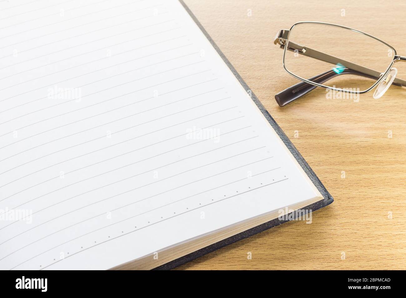 Eyeglasses and open note book with blank page on wood table Stock Photo ...