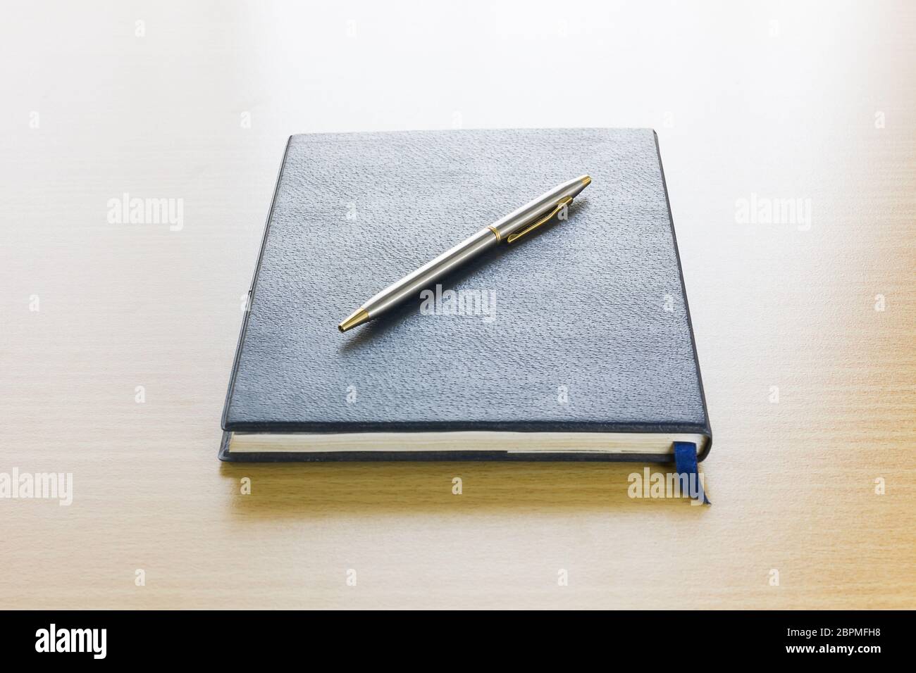 Pen on a book with deck wood background Stock Photo - Alamy