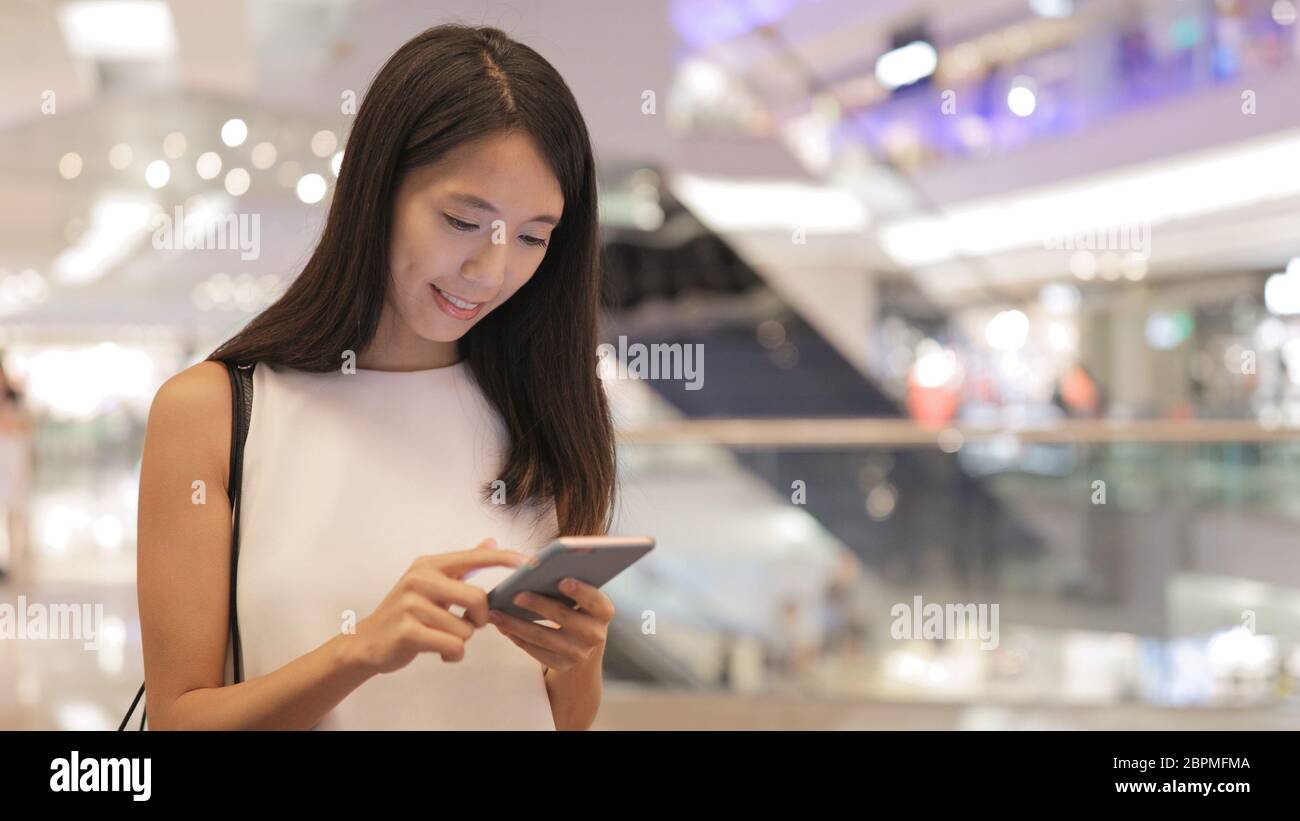 Young Woman use of mobile phone in shopping mall Stock Photo - Alamy