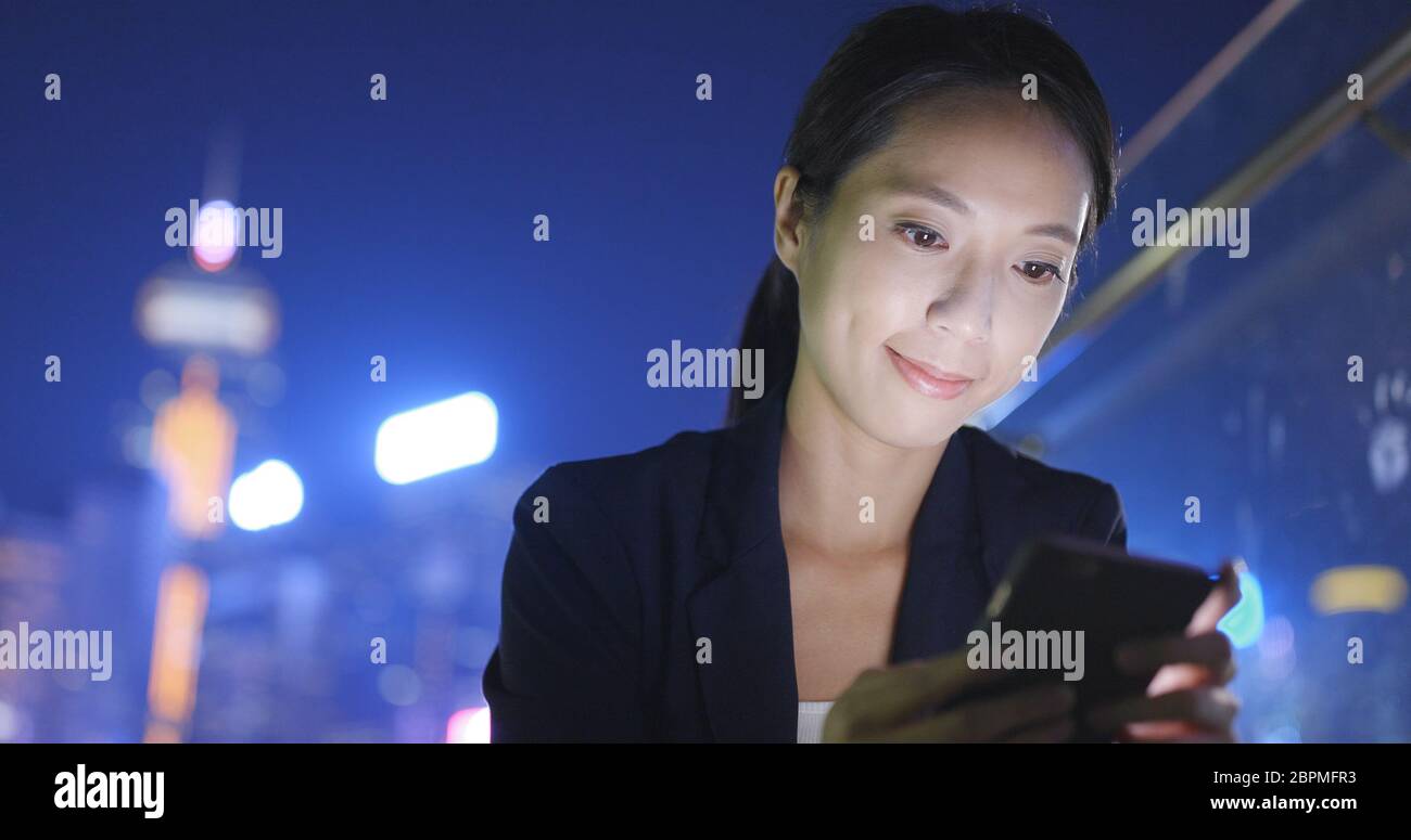 Business woman use of mobile phone at night Stock Photo - Alamy