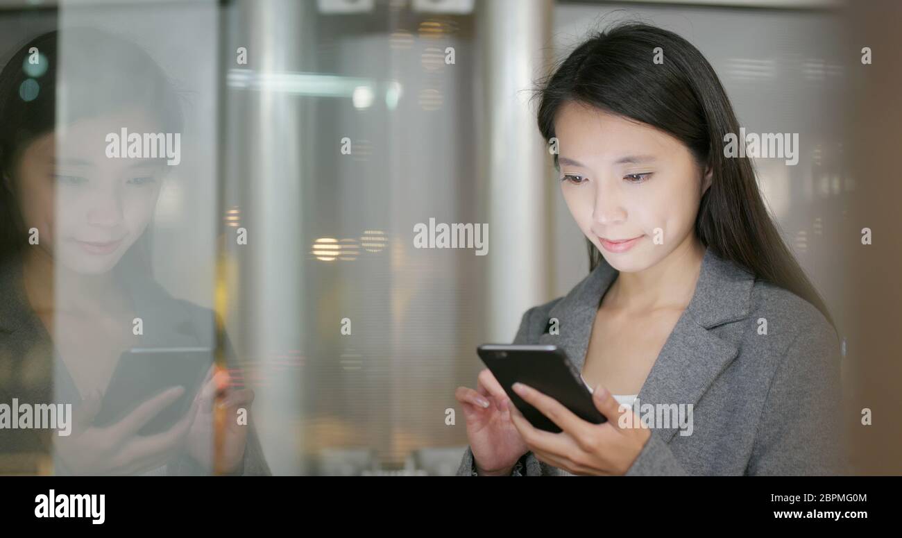 Business woman use of mobile phone with window reflection at night ...