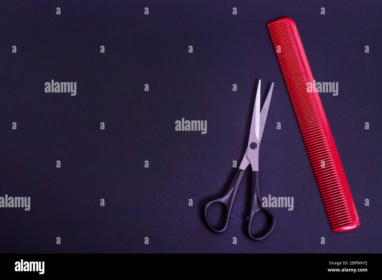 Hairdressing scissors with a red comb on a black background with copy ...