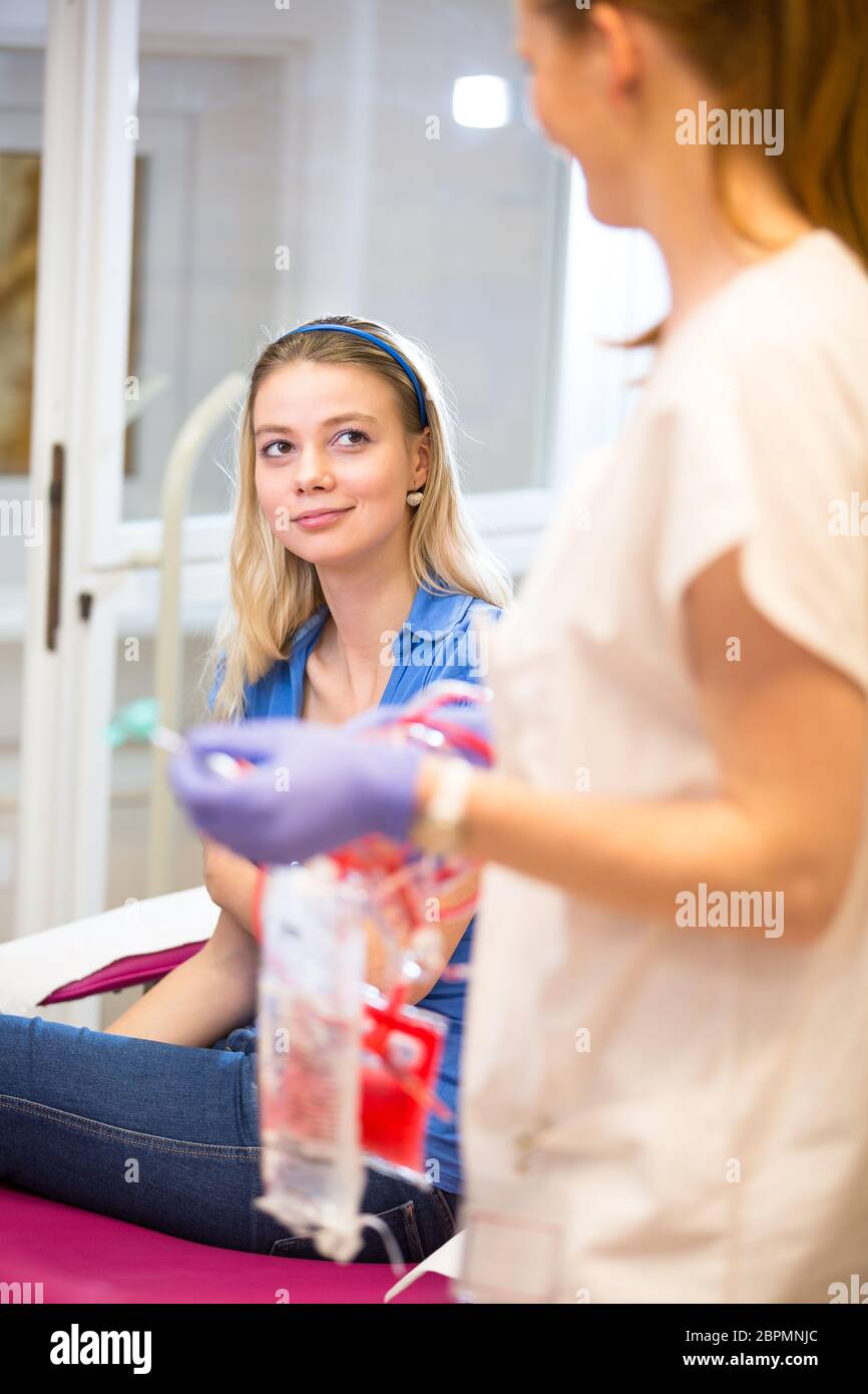 Young woman giving blood in a modern hospital - being given some ...