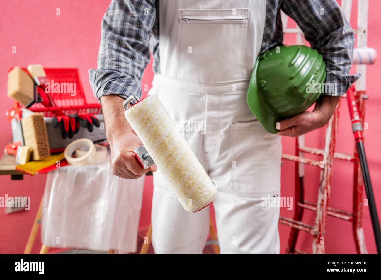 Caucasian house painter worker in white work overalls, with the roller ...