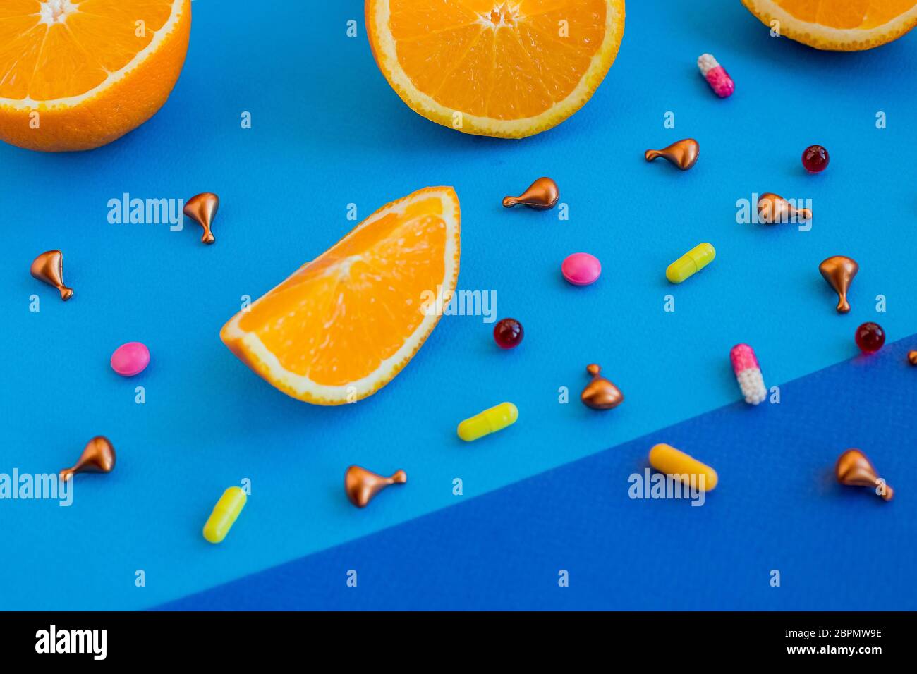 Multivitamins and supplements with fresh orange on blue background ...