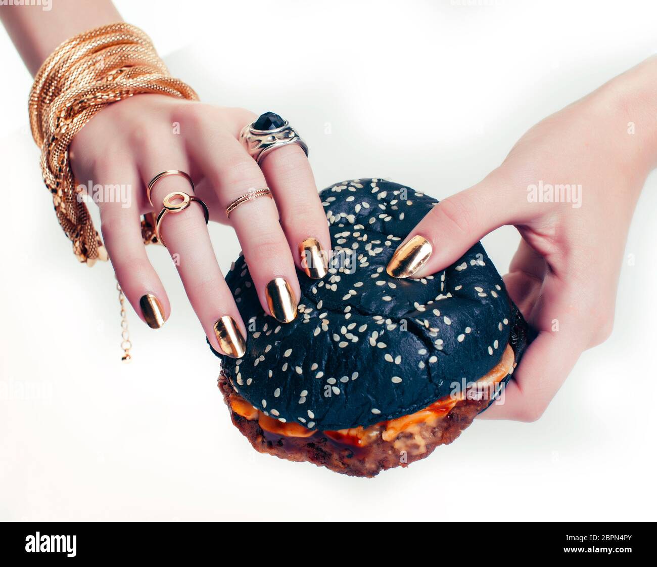 hands of rich woman with golden manicure and jewelry holding black ...
