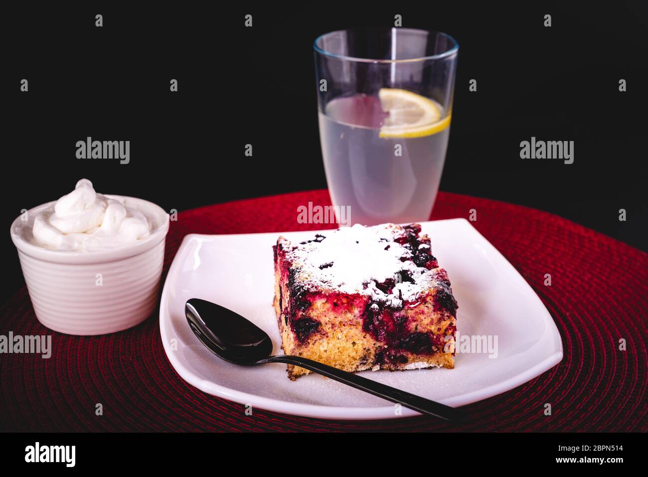 Homemade cake with forest fruit served on a plate with a glass of ...