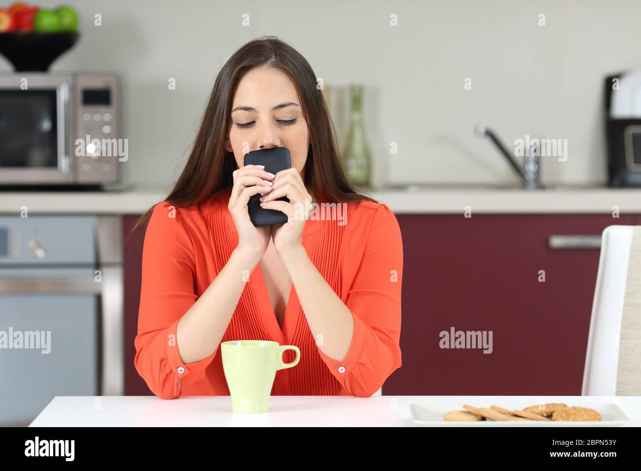 Doubtful woman looking down and wondering if she must call on the phone ...