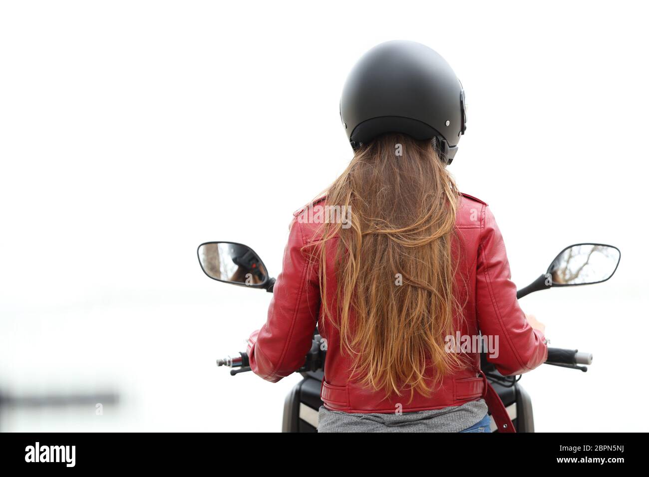 Back view of a motorbiker sitting on a motorcycle on white background ...