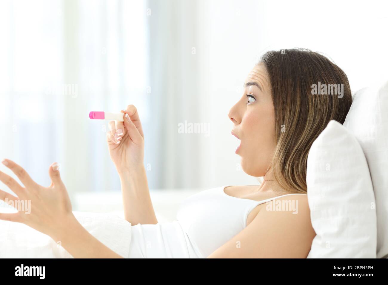 Side view portrait of an amazed woman checking a pregnancy test on the ...