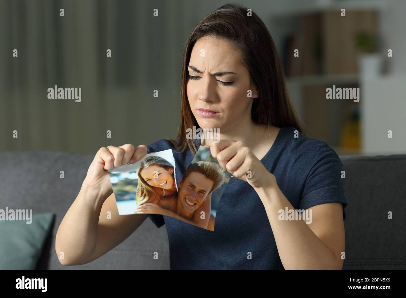 Angry girl breaking a couple photo after breakup sitting on a couch in ...
