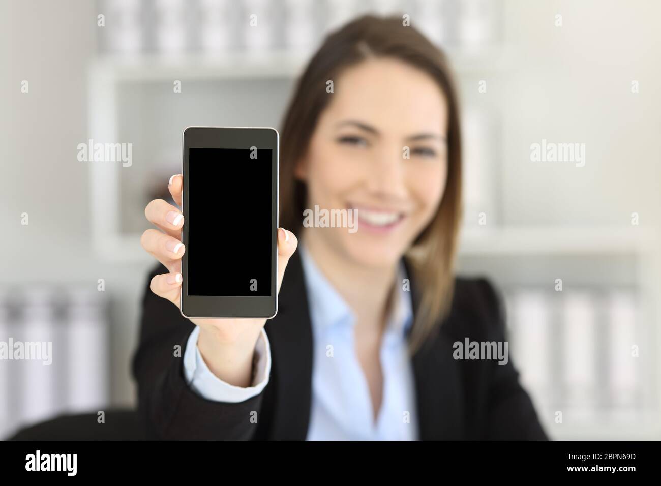 Happy executive showing a blank smart phone screen at office Stock ...