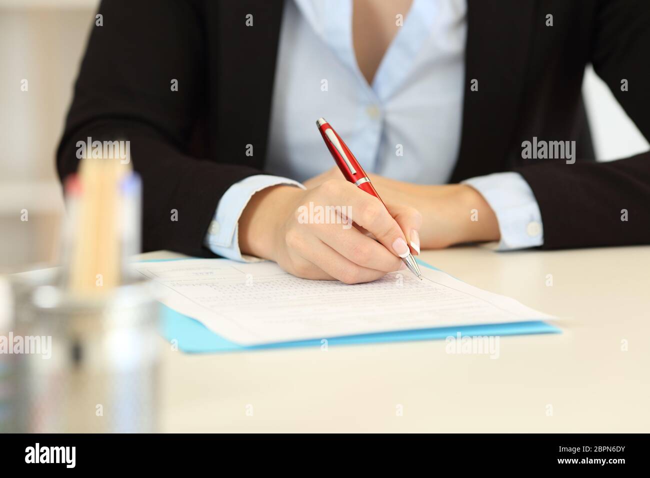 Close up front view of an office worker hands filling form on a desktop ...