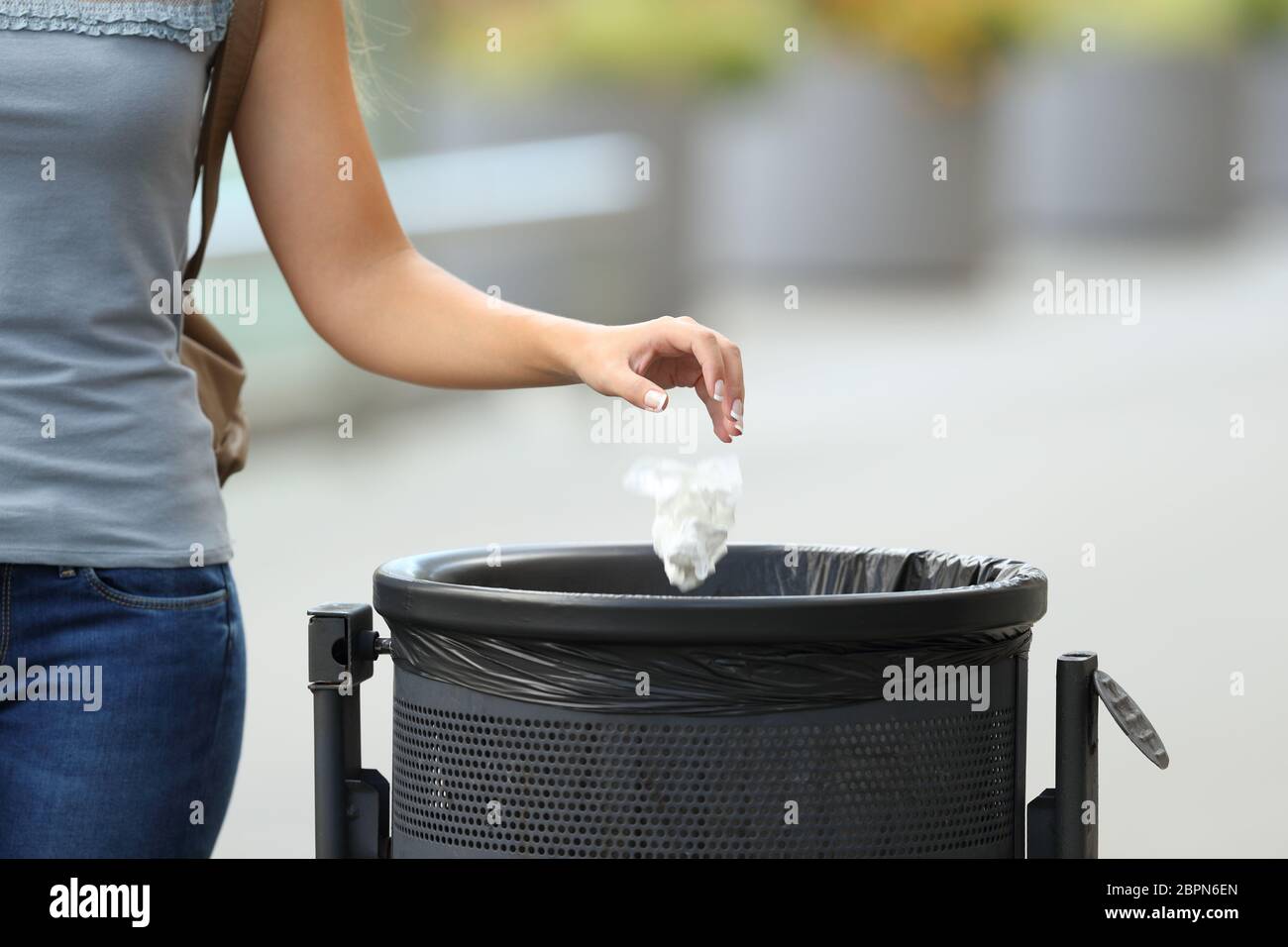 Close up of a civic woman hand throwing garbage in a trash bin on the ...