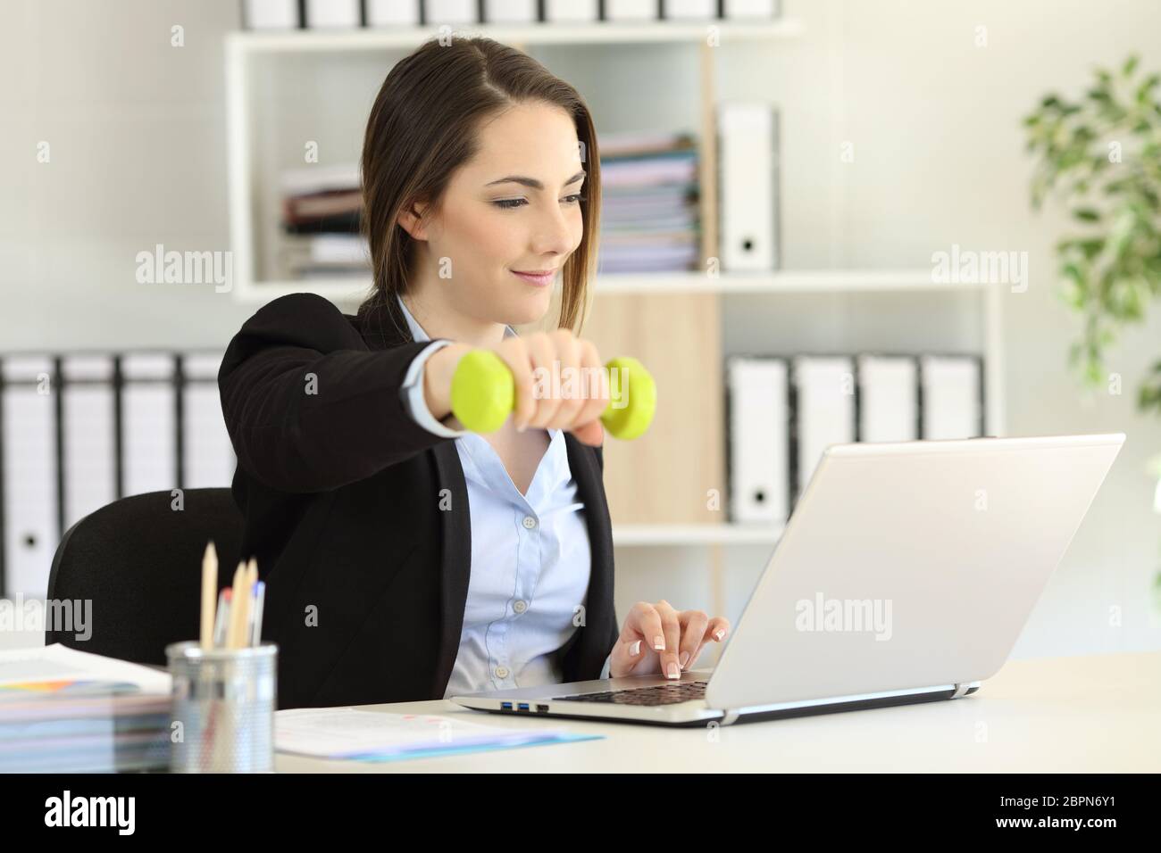 Executive exercising doing weights and working at office Stock Photo ...